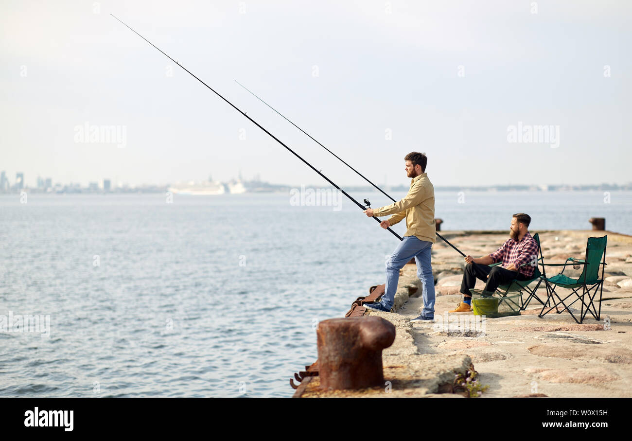 happy friends with fishing rods on pier Stock Photo - Alamy