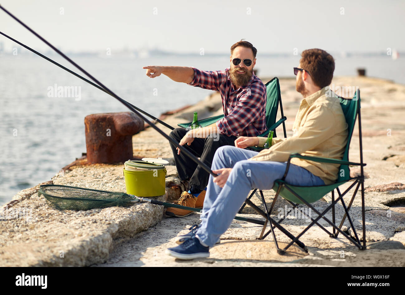 happy friends with fishing rods on pier Stock Photo - Alamy