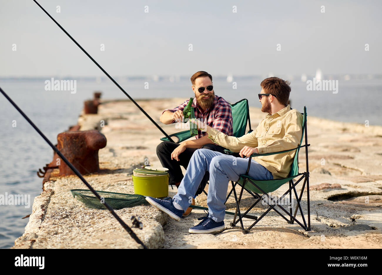 happy friends fishing and drinking beer on pier Stock Photo - Alamy