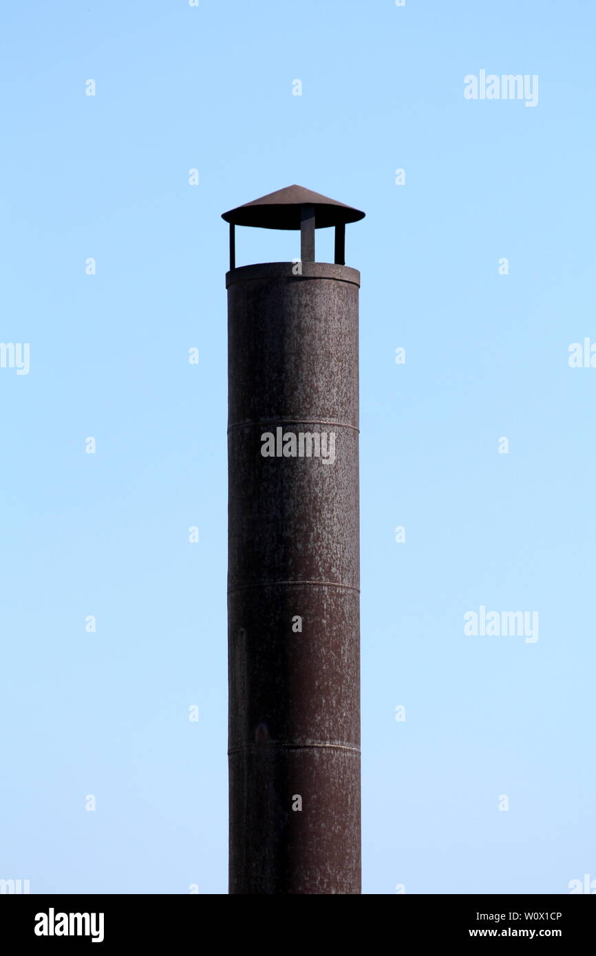 Dark rusted metal industrial chimney with improvised cap on top on ...