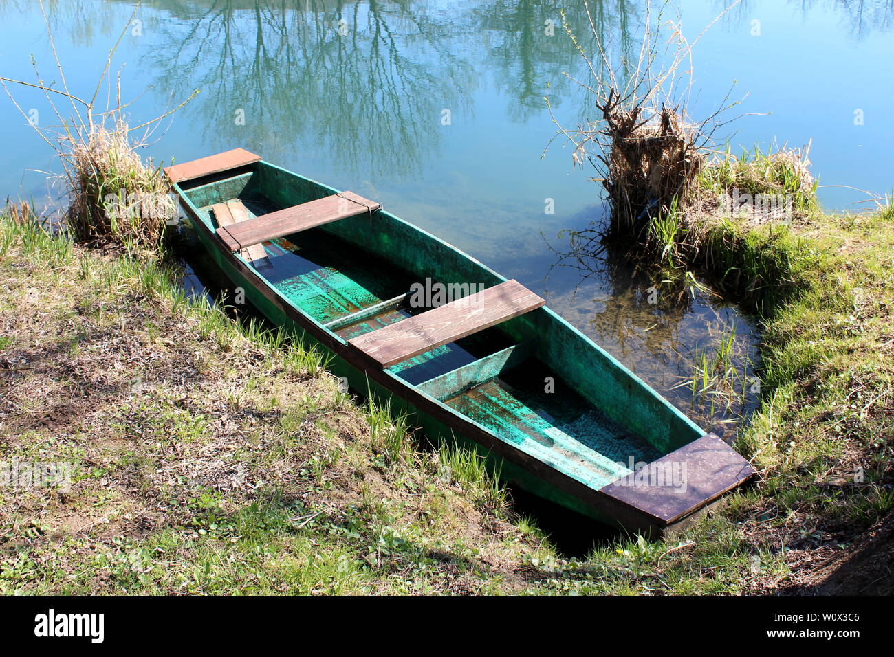 Dilapidated river boat with faded paint secured at local river bank ...