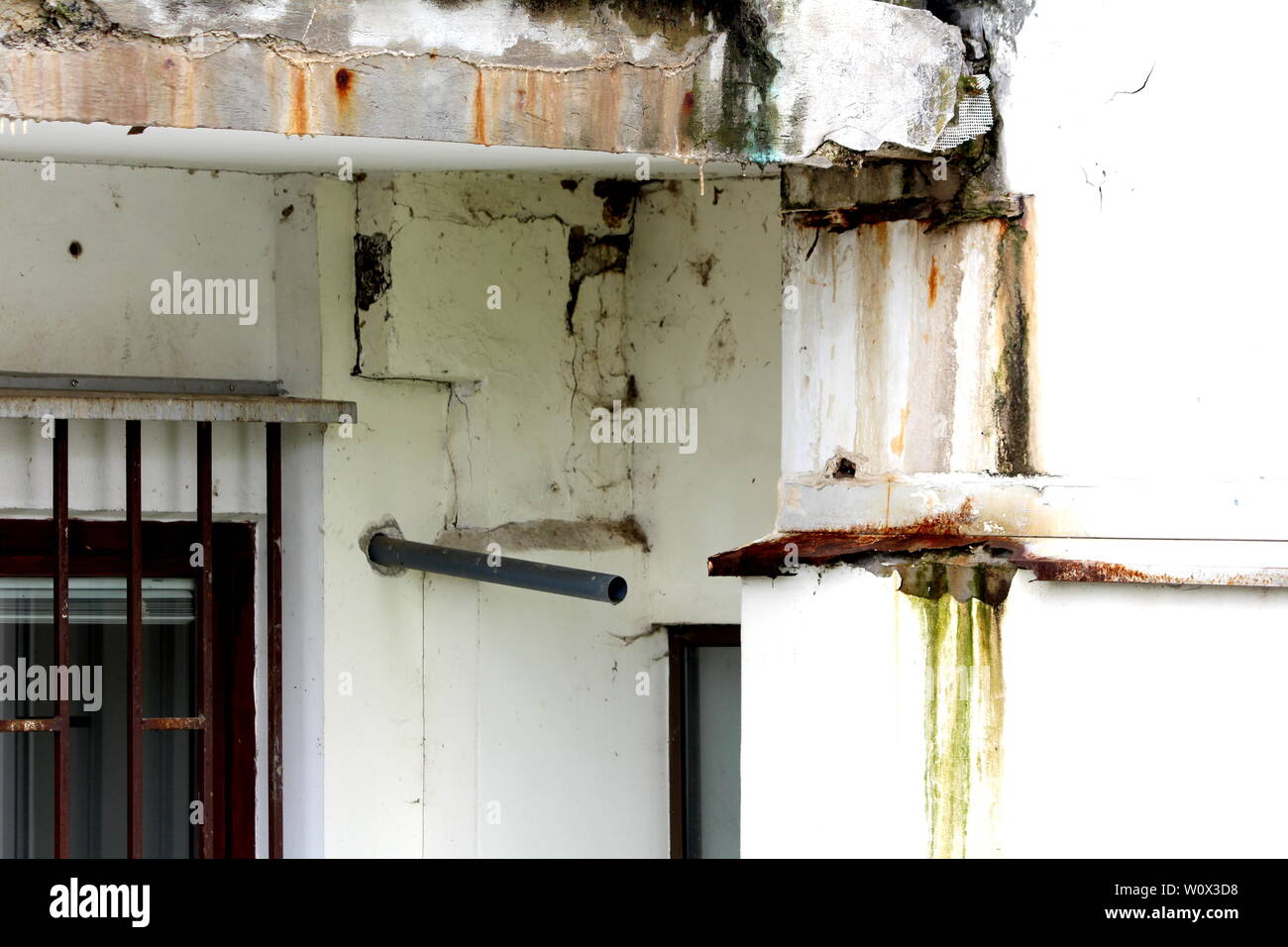 Dirty dilapidated cracked white corner building facade with rusted ...
