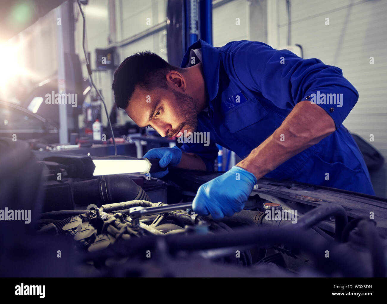 mechanic man with lamp repairing car at workshop Stock Photo - Alamy