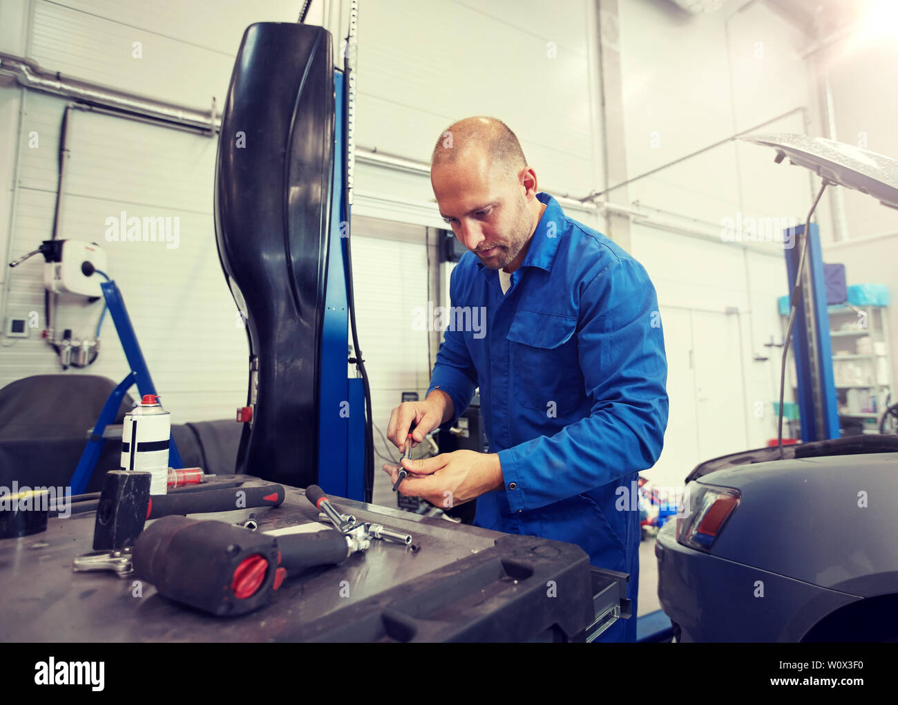 mechanic man with wrench repairing car at workshop Stock Photo - Alamy