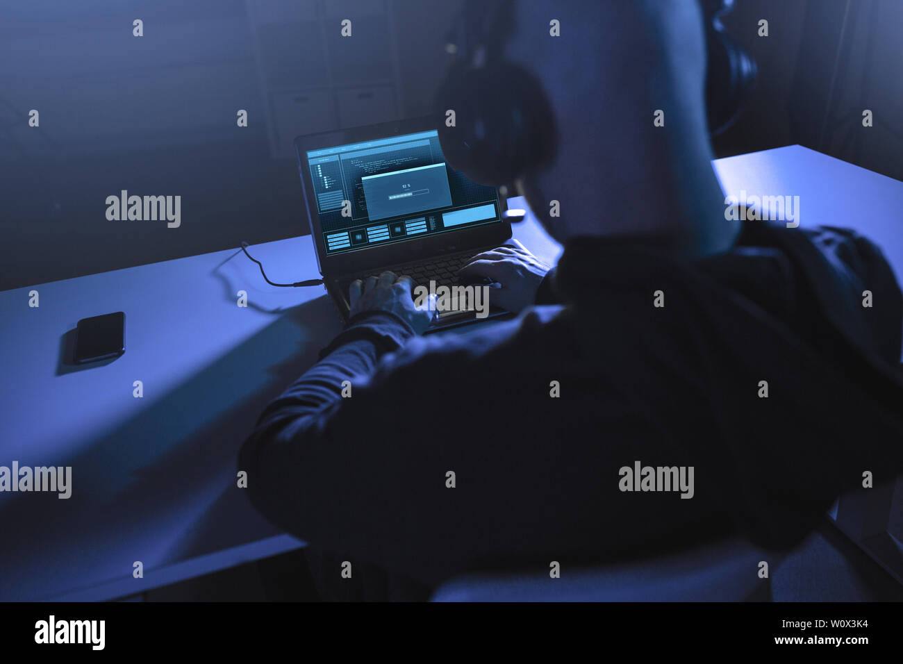 hacker with loading bar on laptop in dark room Stock Photo - Alamy