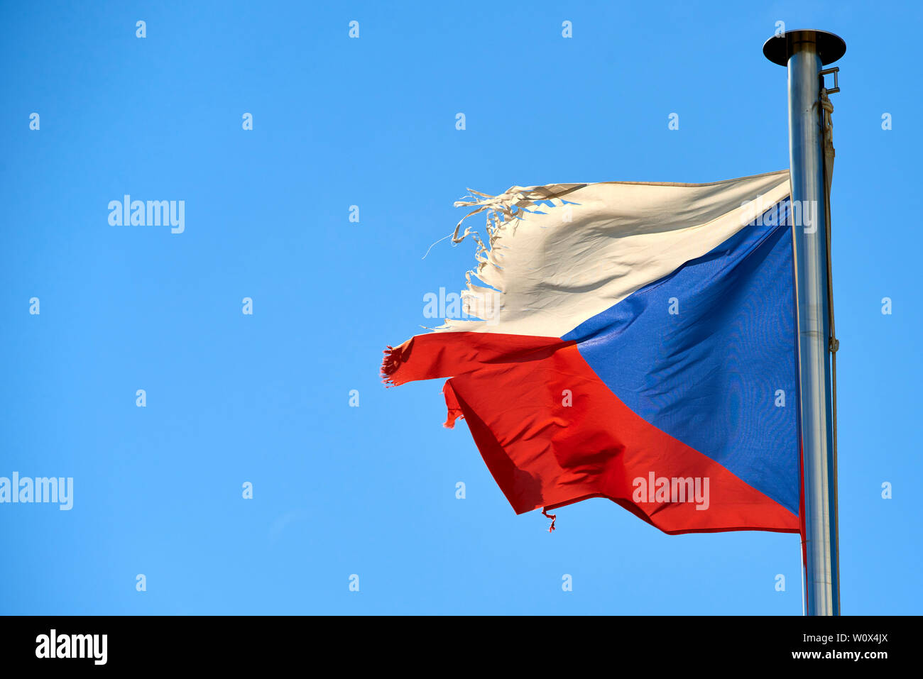 Tattered Czech Republic flag against blue sky blowing in the wind with ...