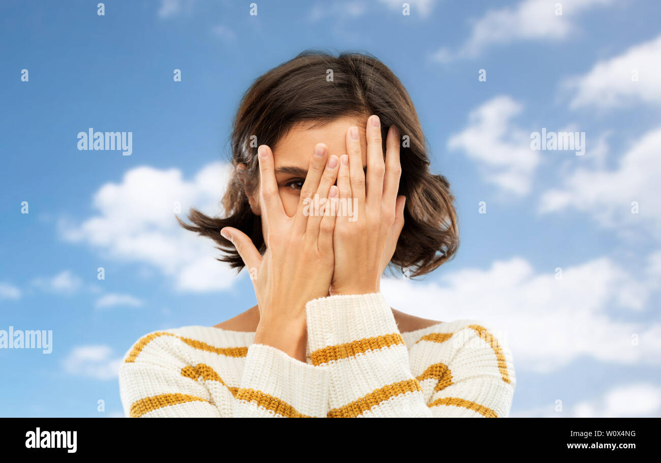 young woman looking by one eye through her fingers Stock Photo - Alamy