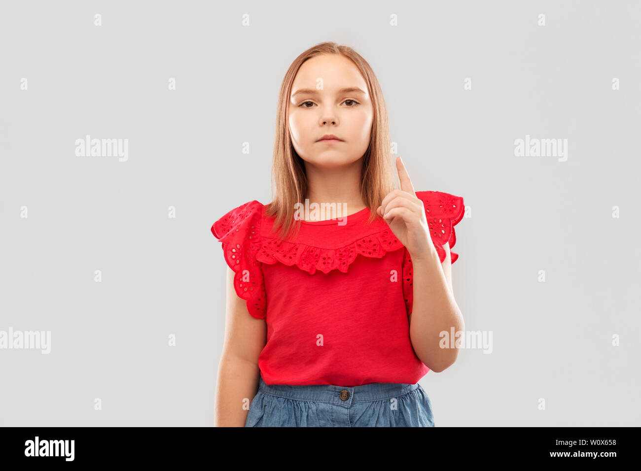 serious girl in red shirt pointing finger up Stock Photo - Alamy
