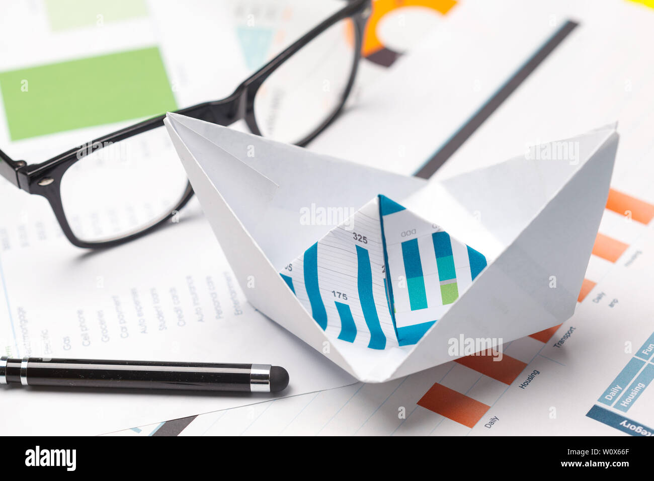 Boats made of paper graph on notebook with glasses and pen.Business ...