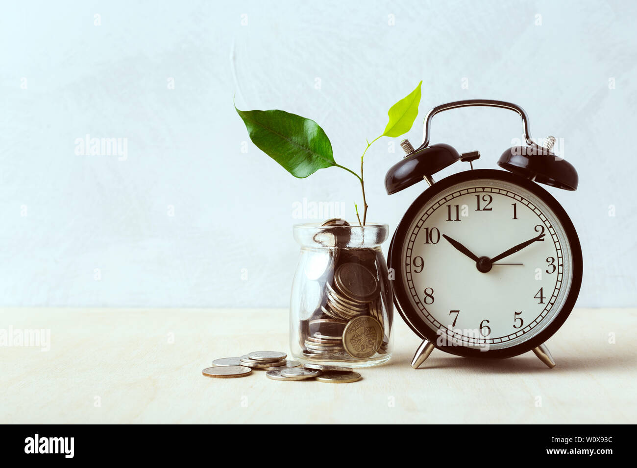 Time is money, table clock with coins Stock Photo - Alamy