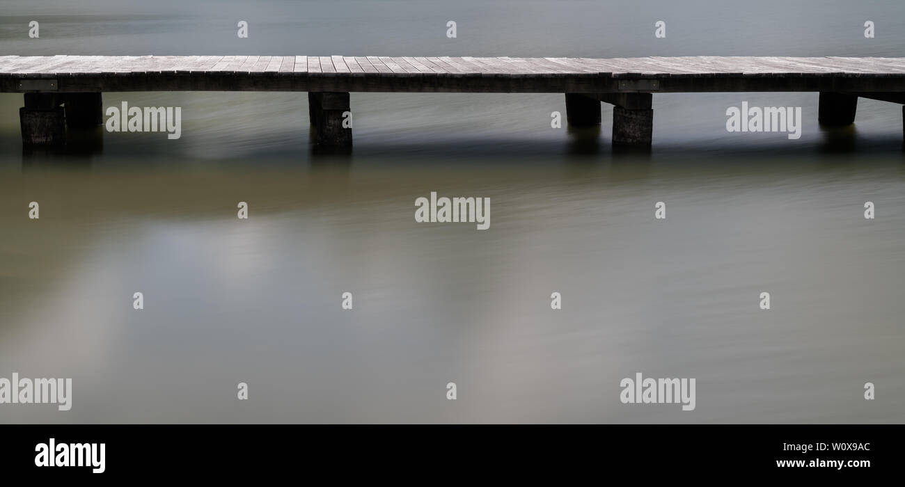 Horizontal view of a long wooden boardwalk on a calm and placid ...