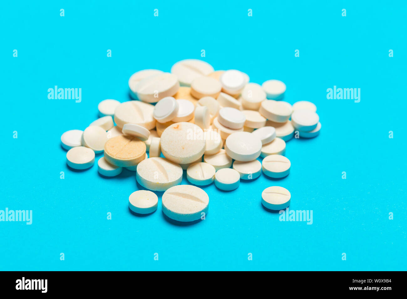 Pills are scattered over a blue background Stock Photo - Alamy