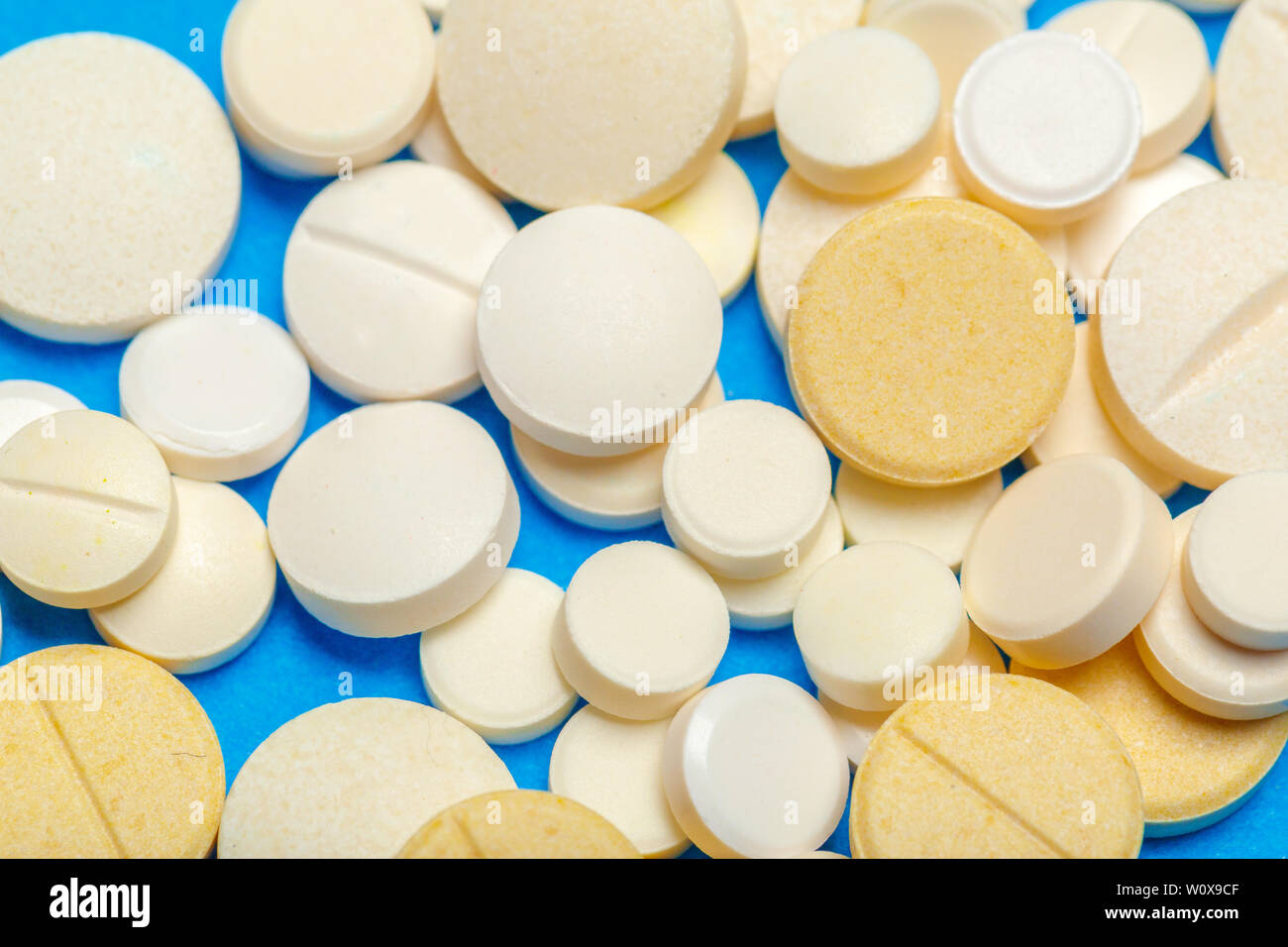 Pills are scattered over a blue background Stock Photo - Alamy