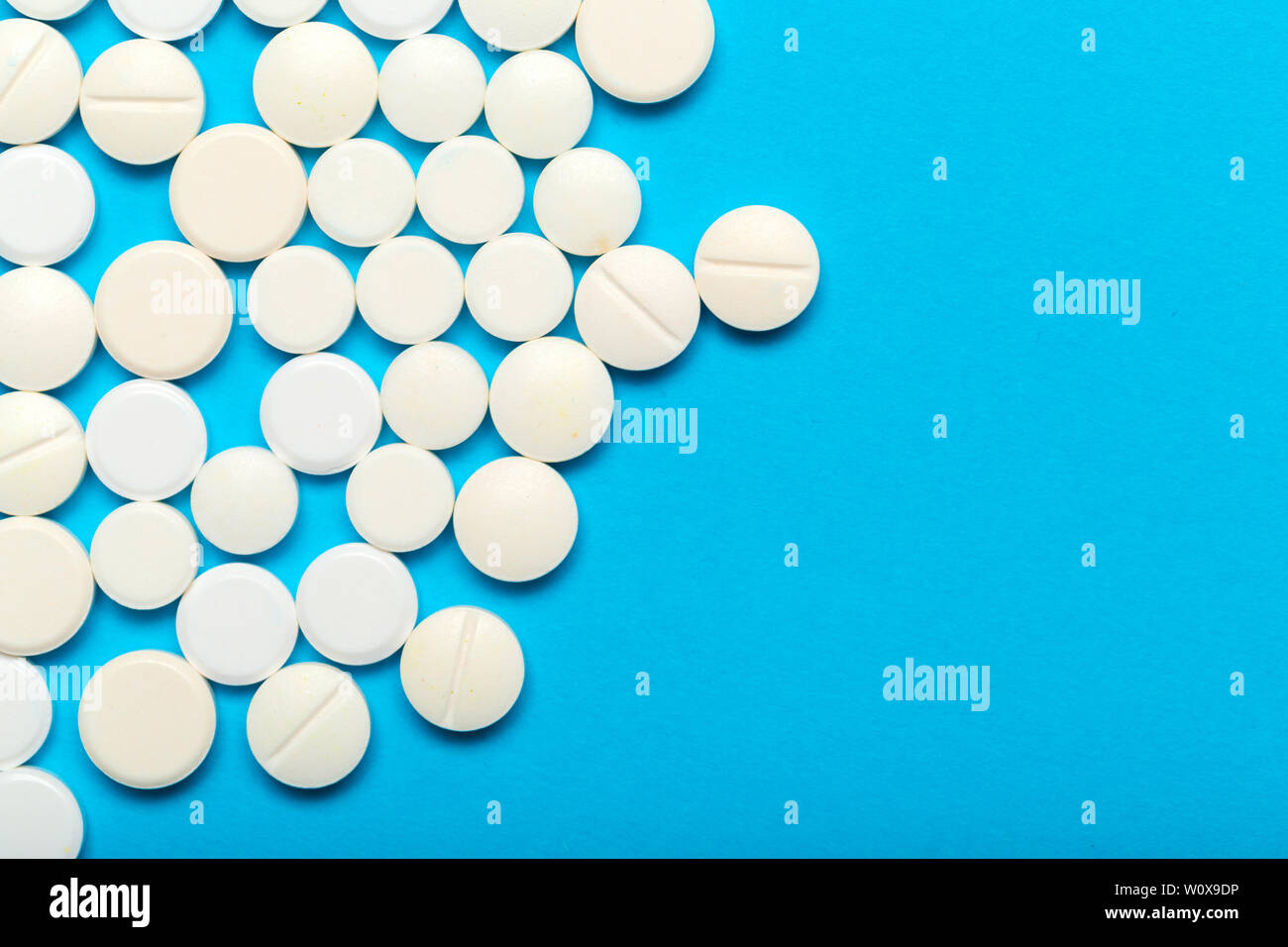 Pills are scattered over a blue background Stock Photo - Alamy