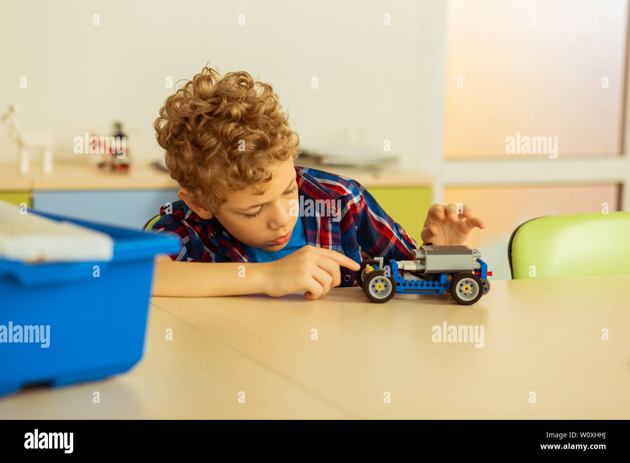 Does it move. Serious cute boy touching a car model while wanting to ...