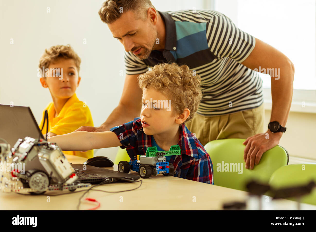 Computer class. Smart cute boy sitting in front of the laptop while ...