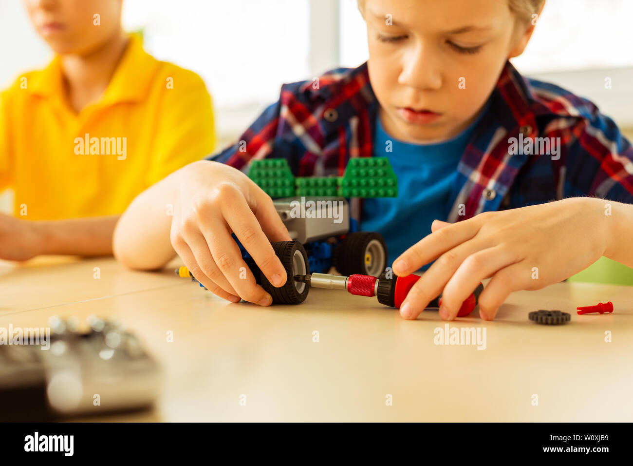 Process of construction. Smart nice boy putting details together while ...