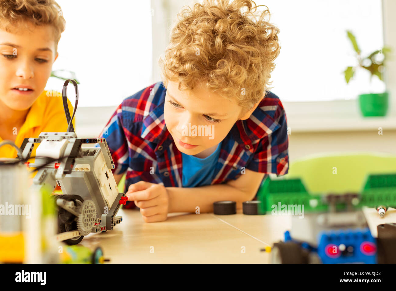 Modern robotics. Nice pleasant boy looking at the robot while being ...