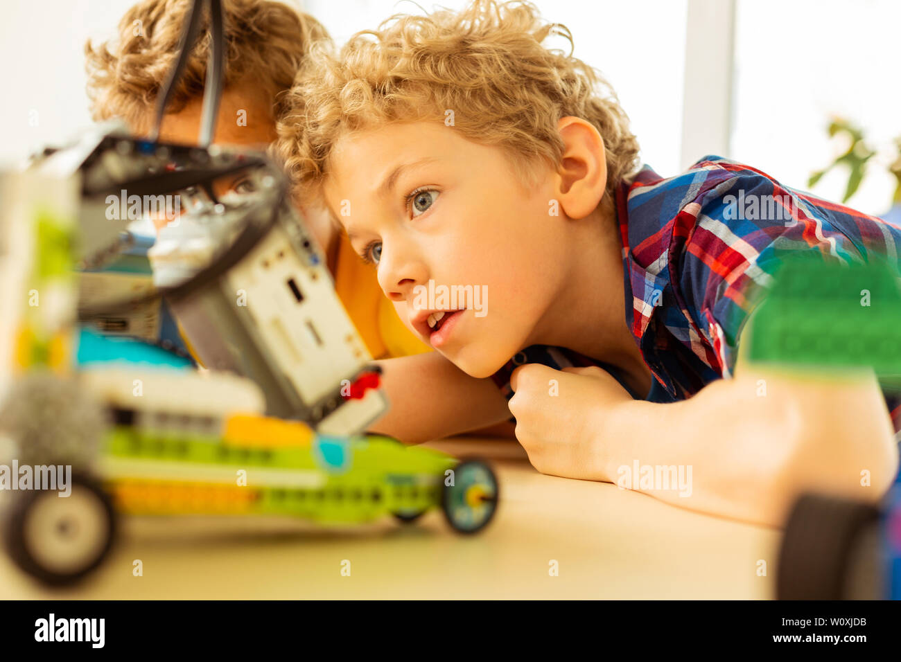 Interesting science. Smart excited boy looking at the robot while being ...