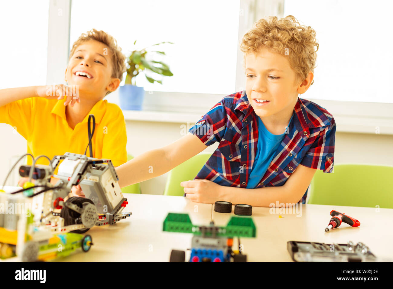 Science of future. Delighted cute boys trying to construct a robot ...