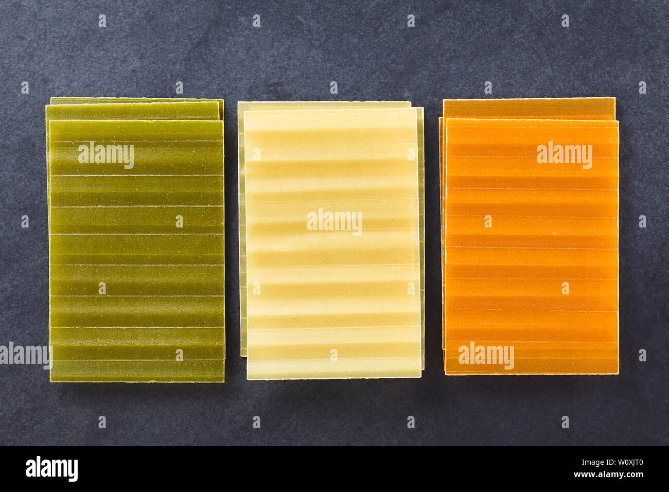 Raw tri color lasagne pasta sheets, photographed overhead on slate ...