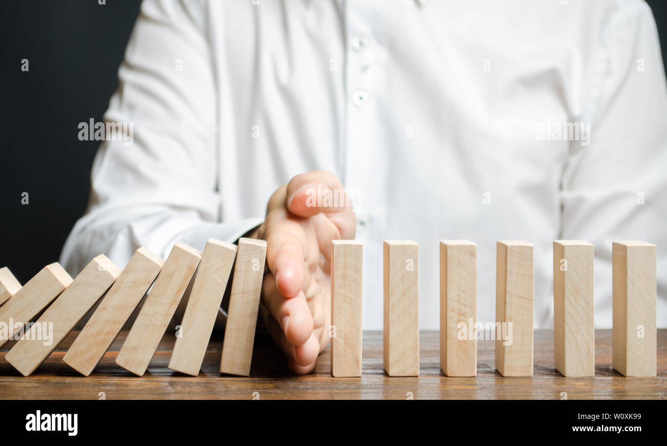 Businessman stops domino falling. Risk management concept. Successful ...