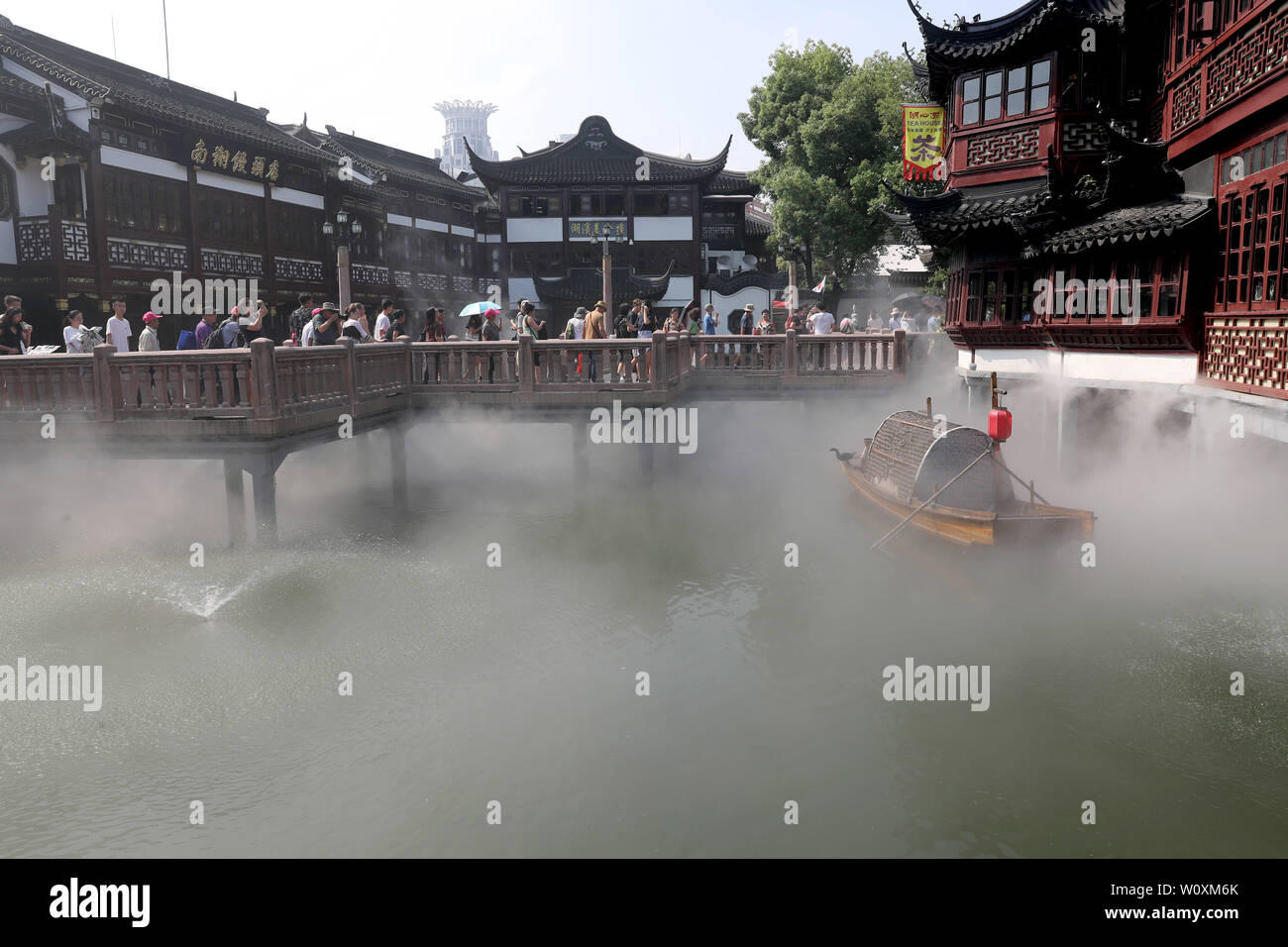 Shanghai. 28th June, 2019. People walk on the Jiuqu Bridge in mist at ...