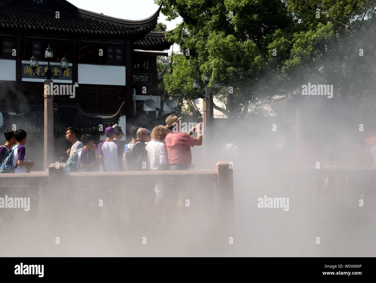 Shanghai. 28th June, 2019. People walk on the Jiuqu Bridge in mist at ...