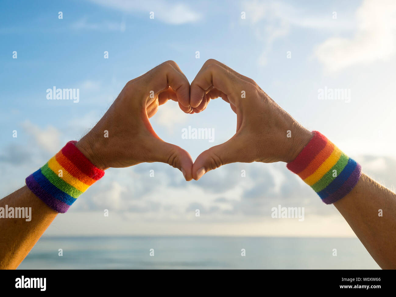 Hands wearing LGBTQI pride rainbow colors sport wristbands making a ...