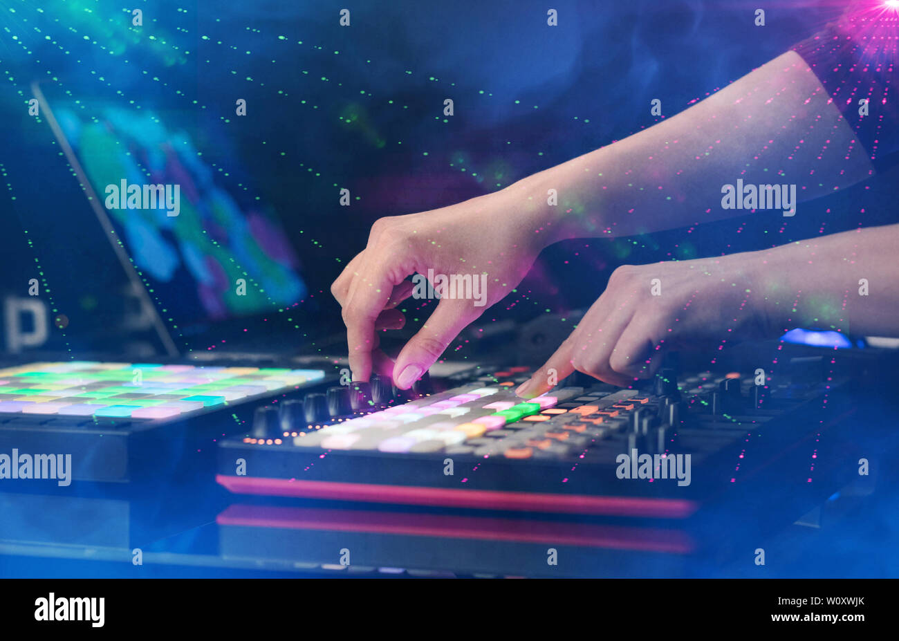 Hand mixing music on midi controller with party club colors around ...