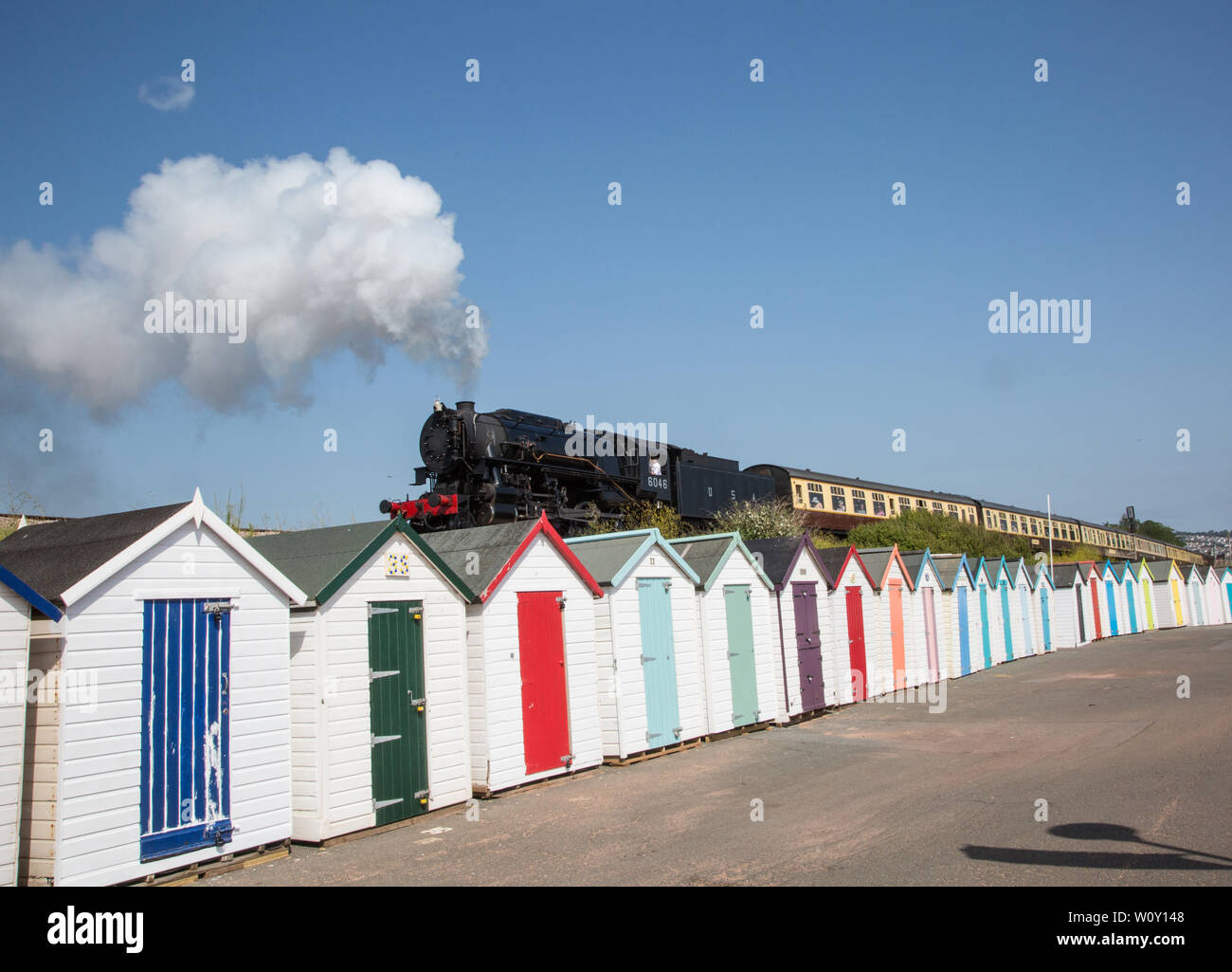 Steam train passing above beach huts on its way to Kingswear on the ...