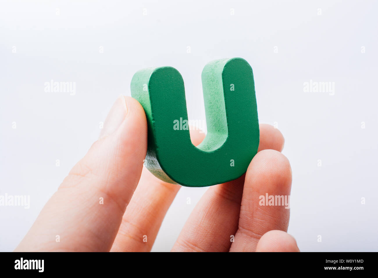 Hand holding letter cube U of made of wood Stock Photo - Alamy