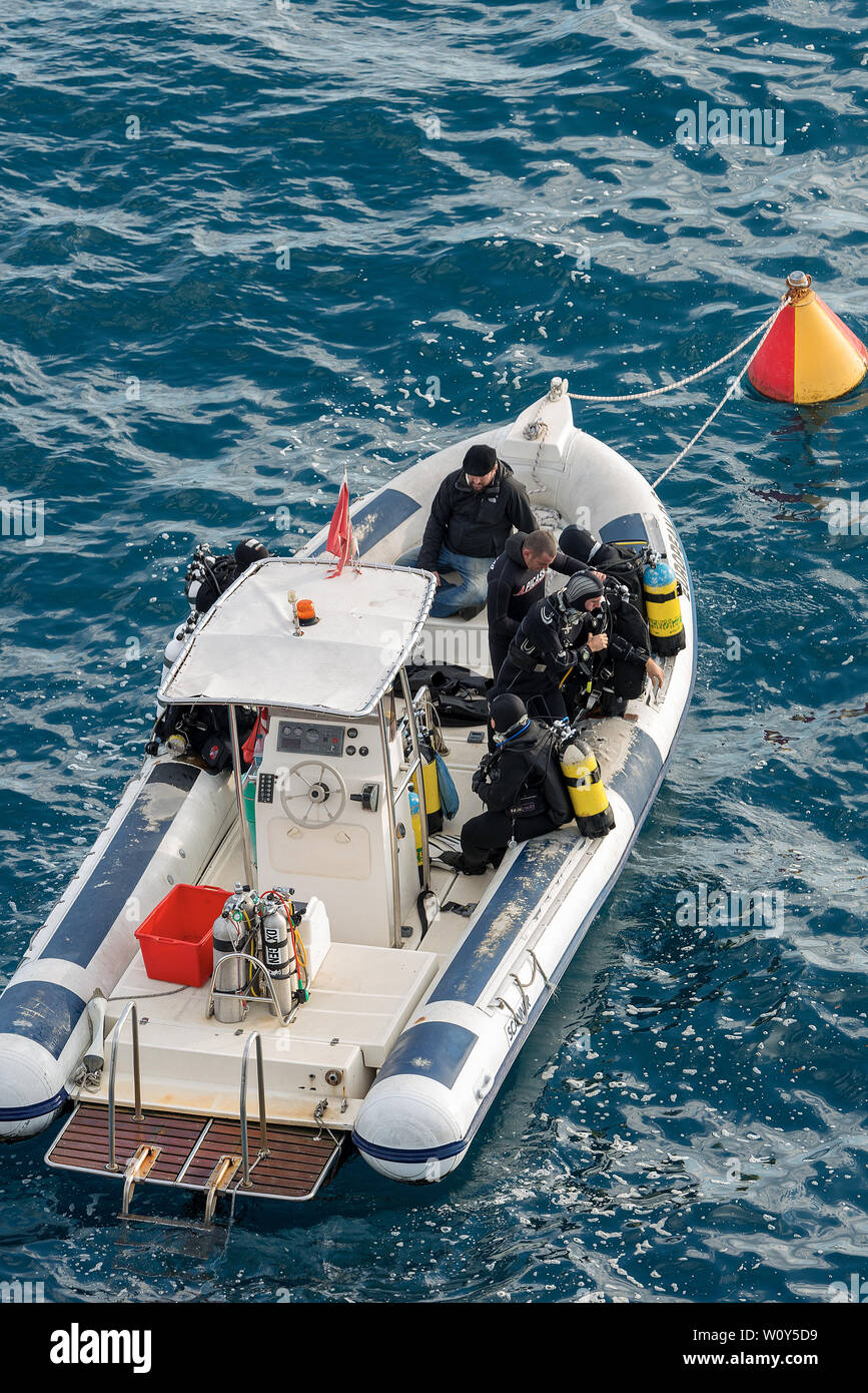 A group of divers on inflatable boat get ready for a dive in the ...