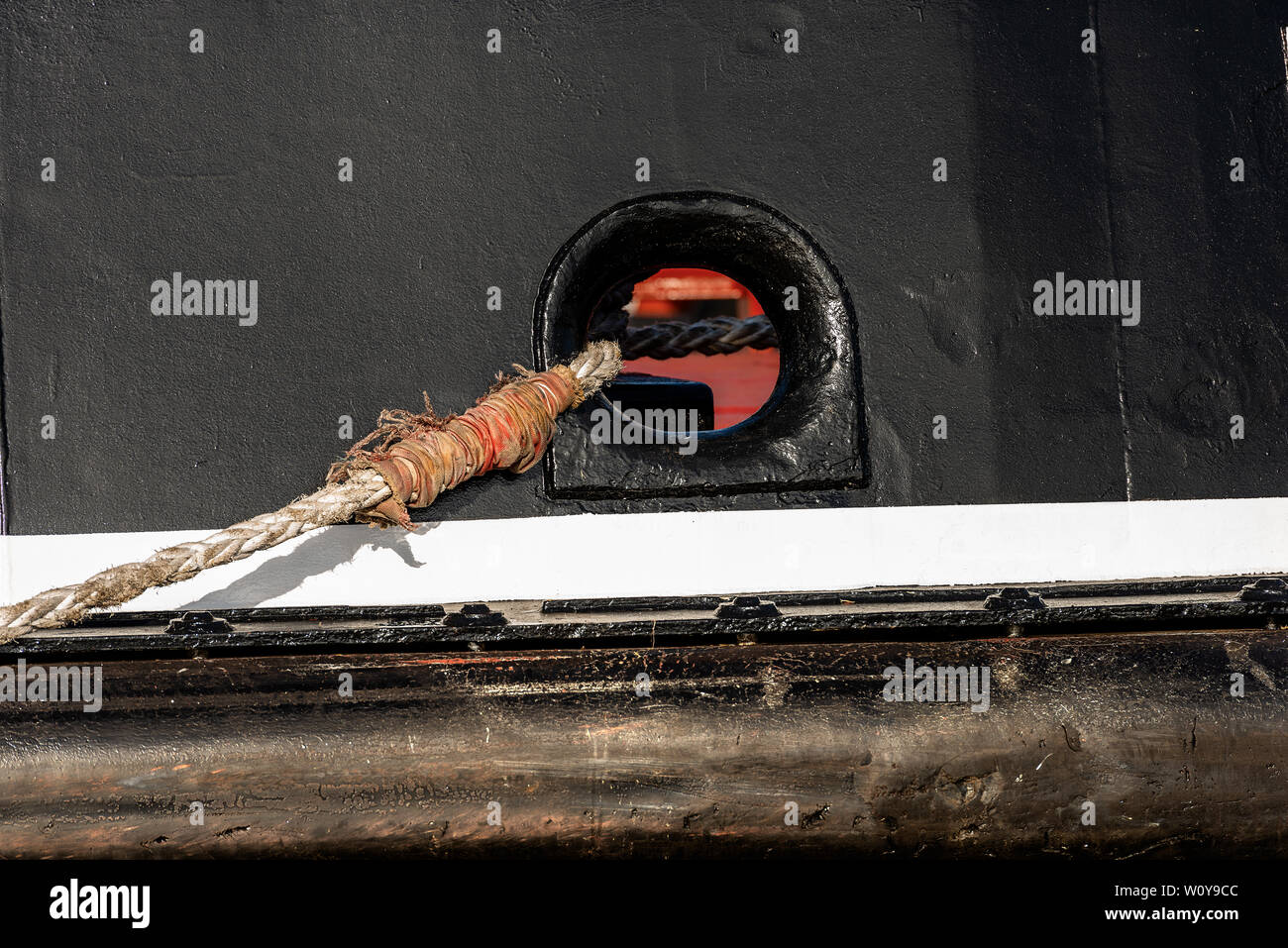 Hawsehole - Detail of a mooring hole with ropes, Black ship in the port ...
