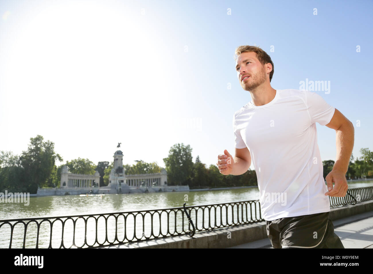 Jogging man running in city park El Retiro Madrid. Male runner ...
