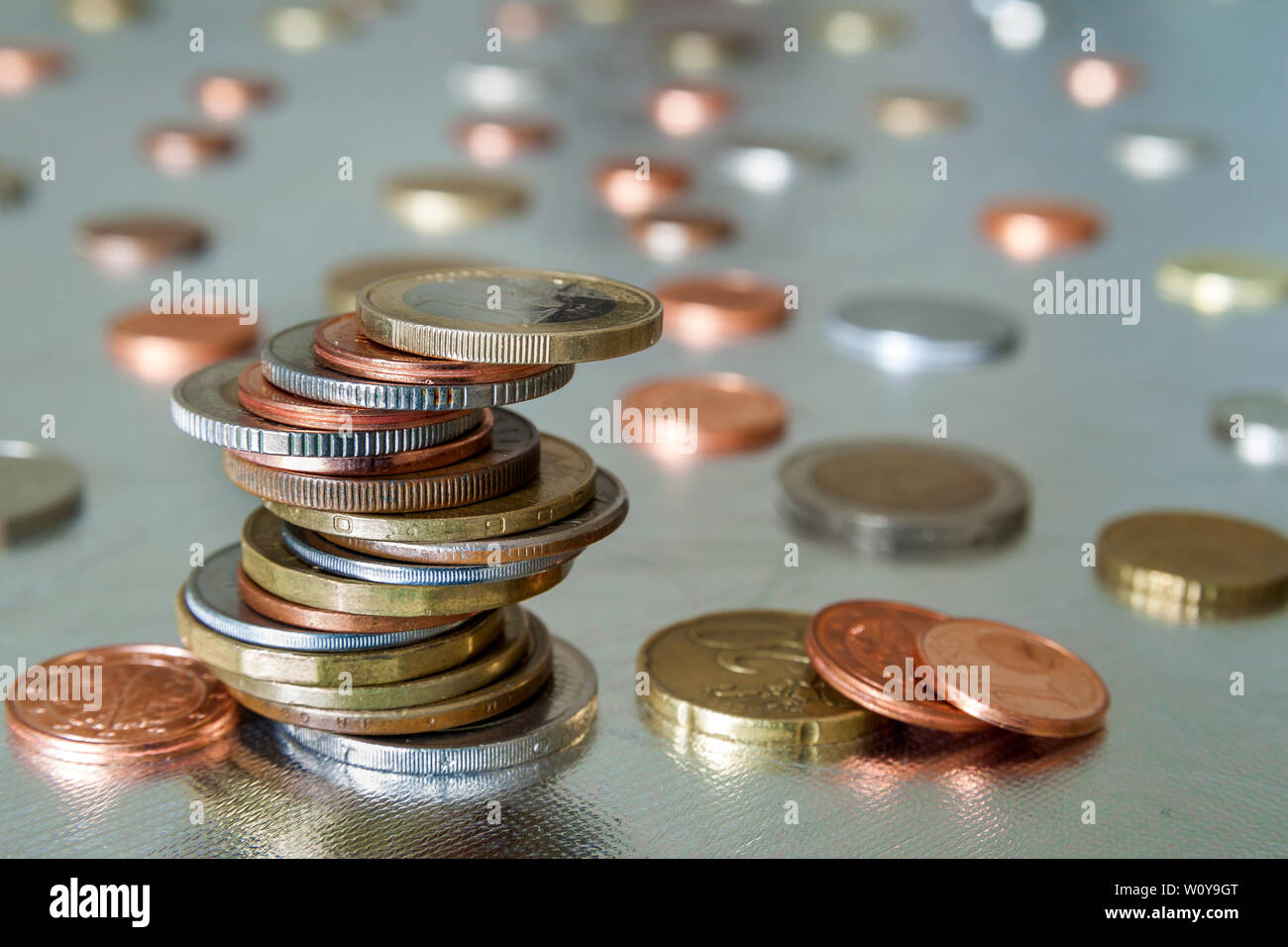 Pile of shiny coins different sizes and colors stacked unevenly on each ...