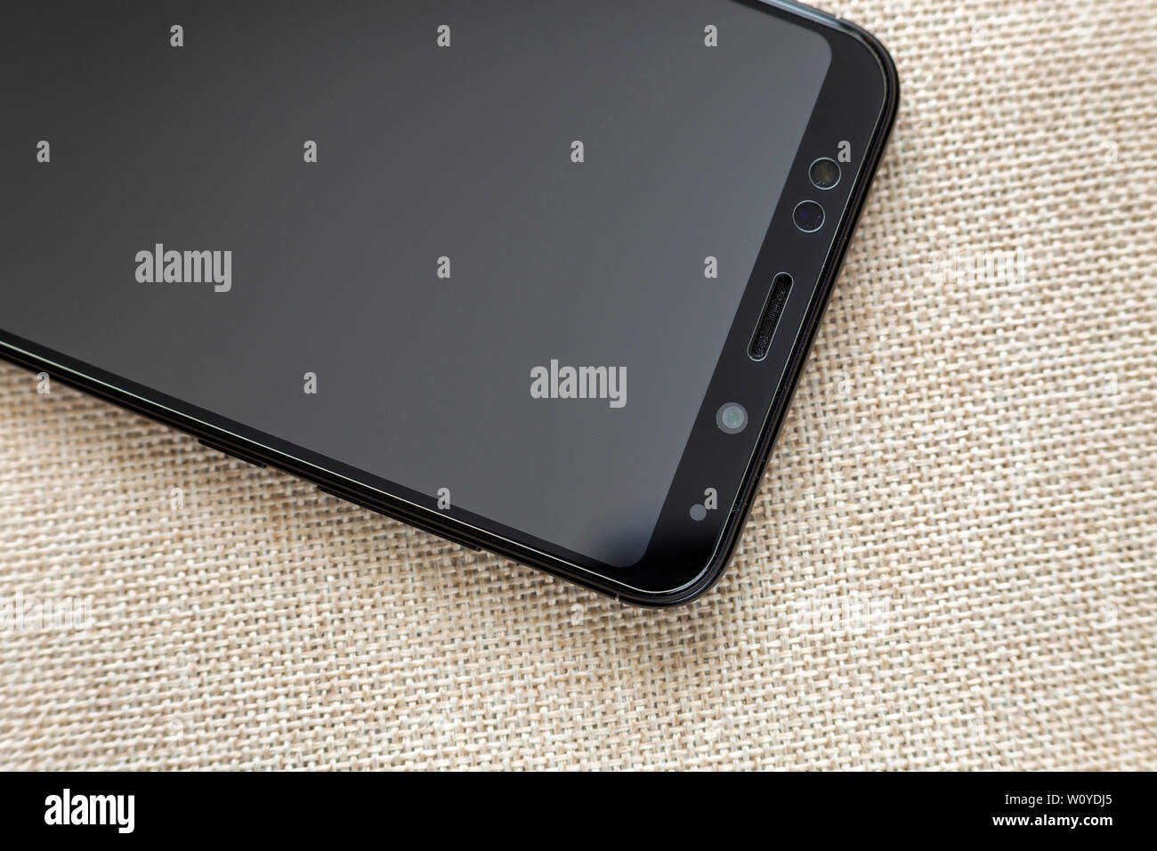 New black modern cellphone isolated on light cloth copy space ...