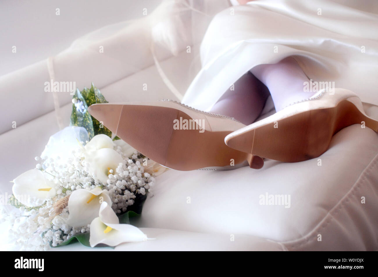Bride feet with shoes and bouquet relaxed on the white sofa Stock Photo ...