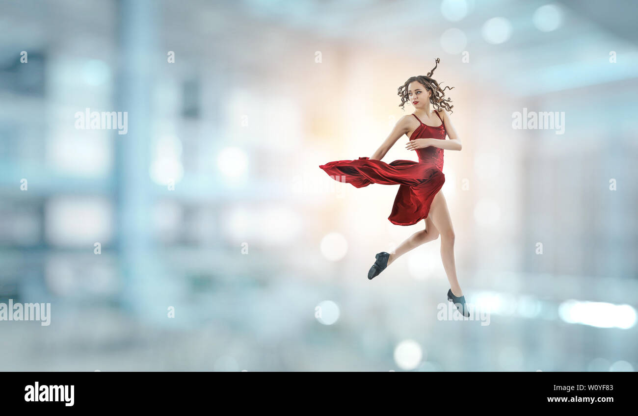 Young and beautiful female dancer in a red dress in a jump. Mixed media ...