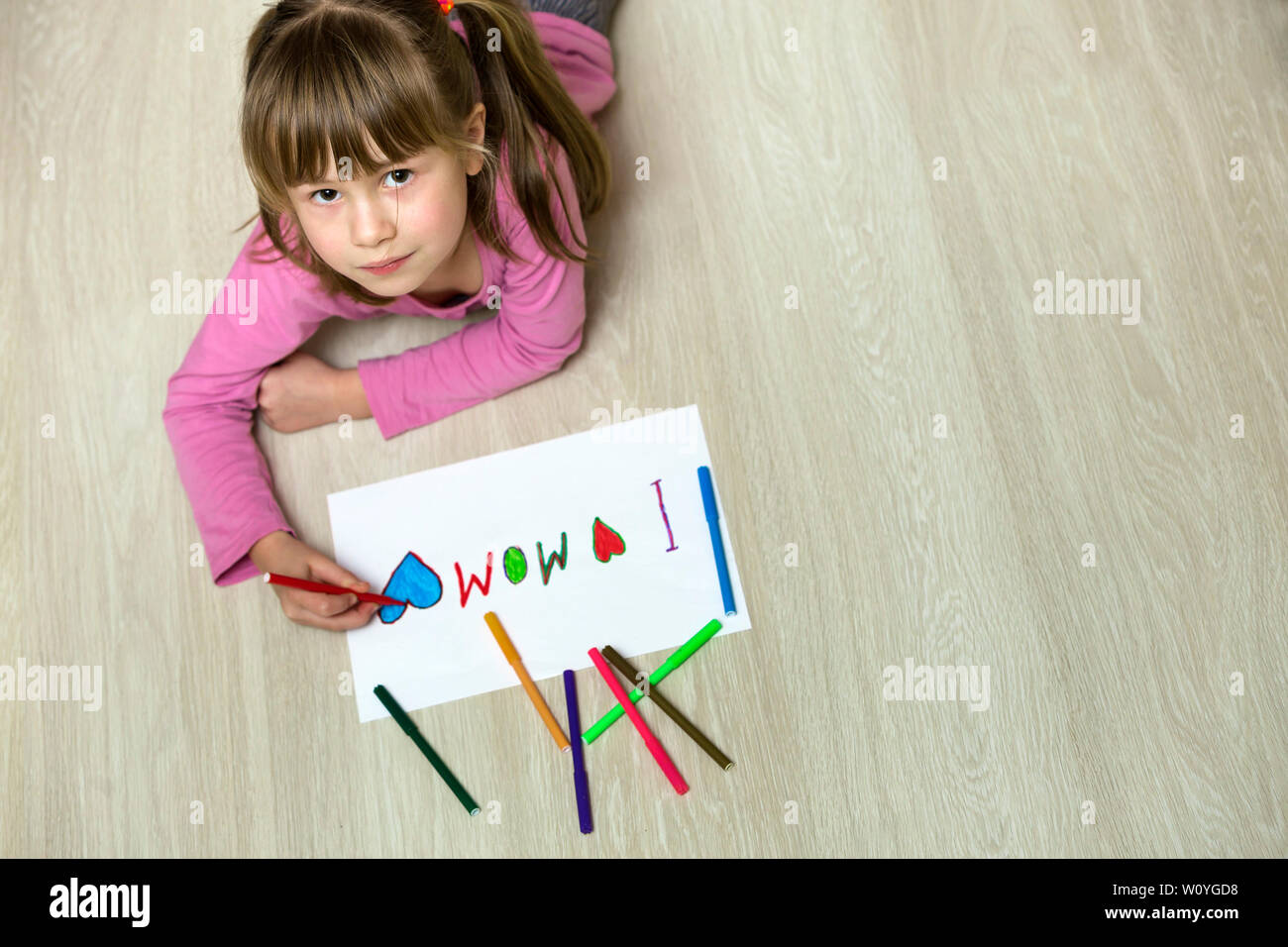 View from above of cute child girl drawing with colorful crayons I love ...