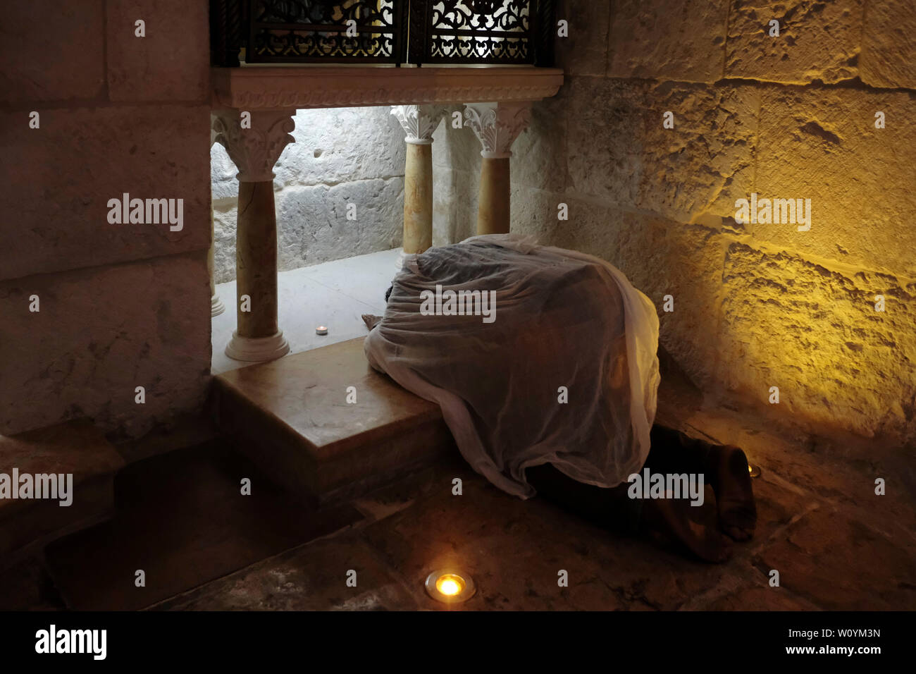 A Christian pilgrim from Africa kneeling in prayer over the altar at ...