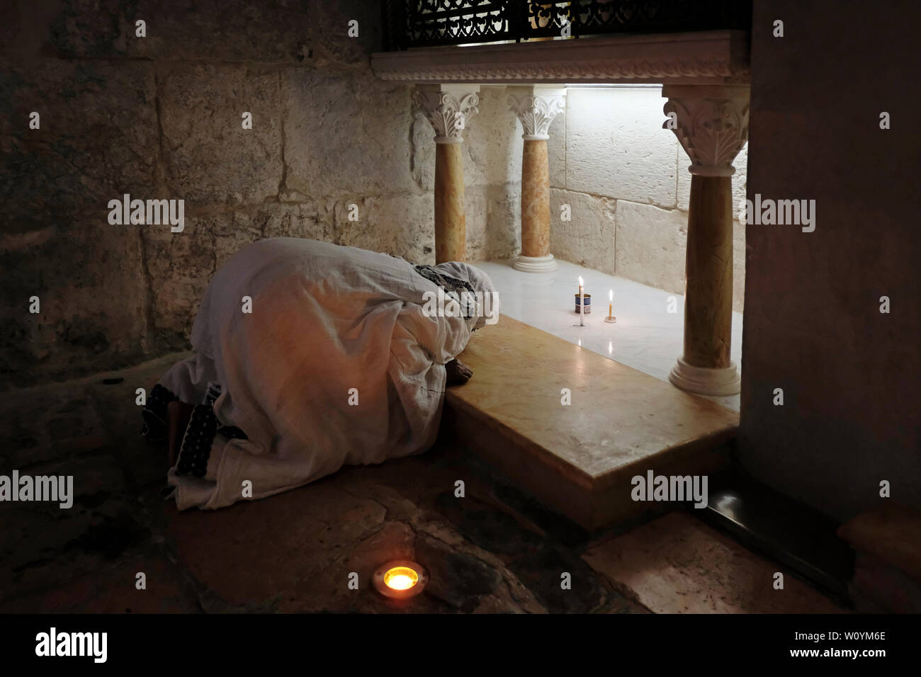 A Christian pilgrim from Africa kneeling in prayer over the altar at ...