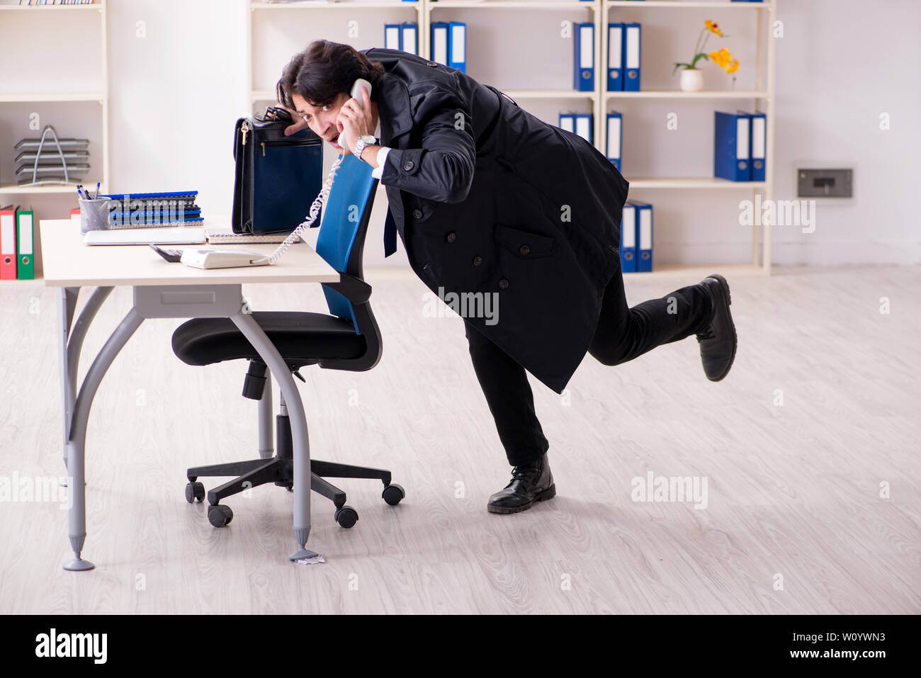 Young male employee in the office in time management concept Stock ...