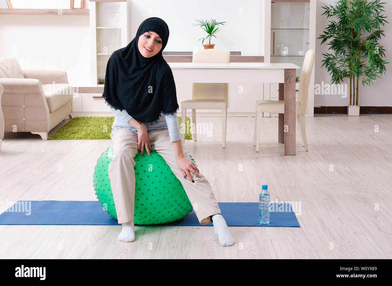 Young woman in hijab doing exercises at home Stock Photo - Alamy