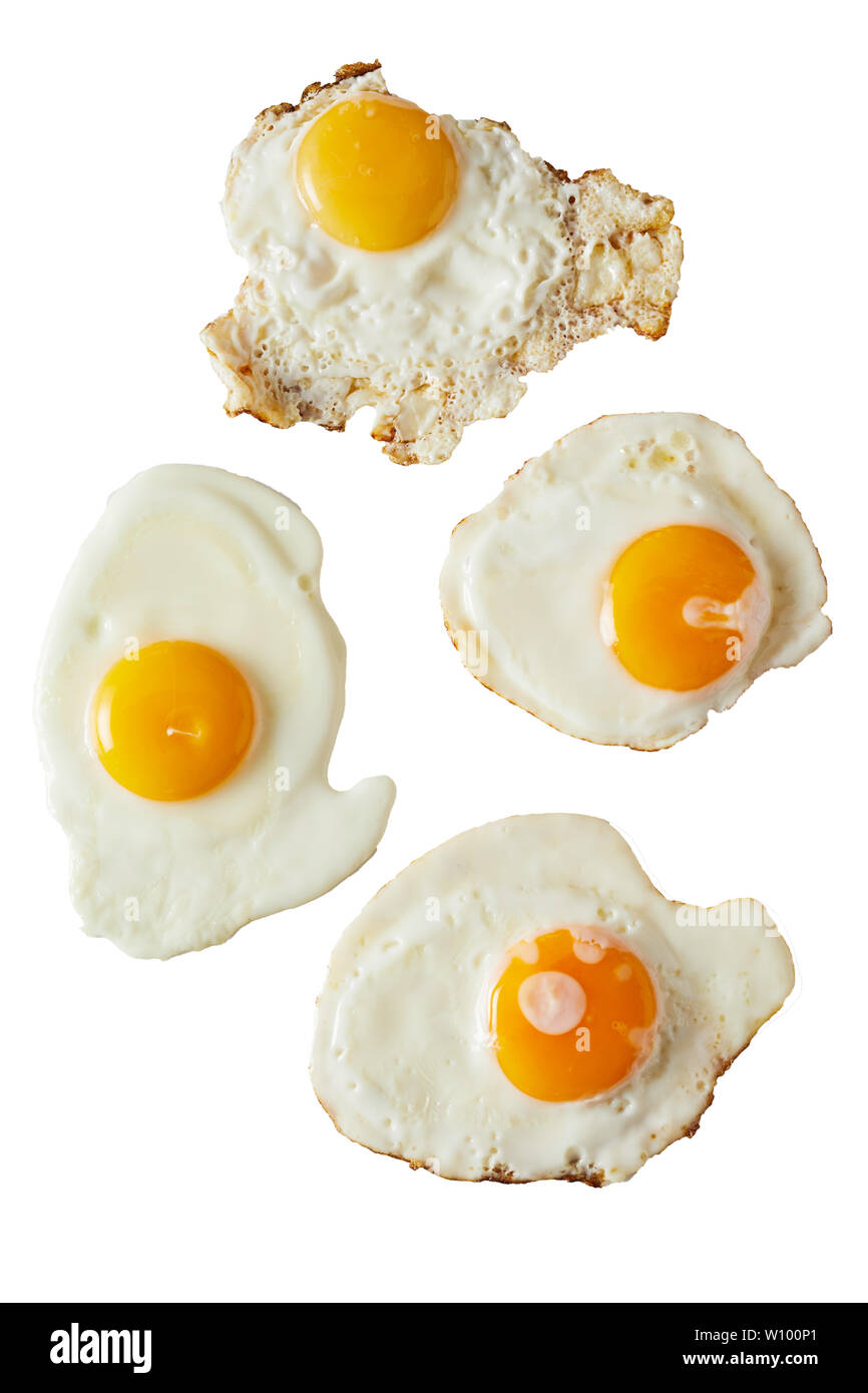 Four fried eggs ranging from soft to crispy with bright yellow yolks isolated on white viewed ...