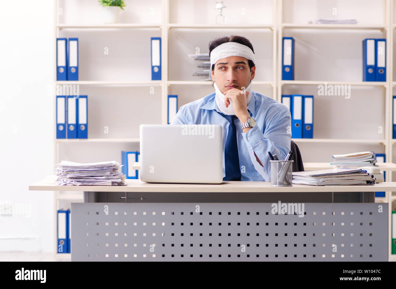 Young injured male employee working in the office Stock Photo - Alamy
