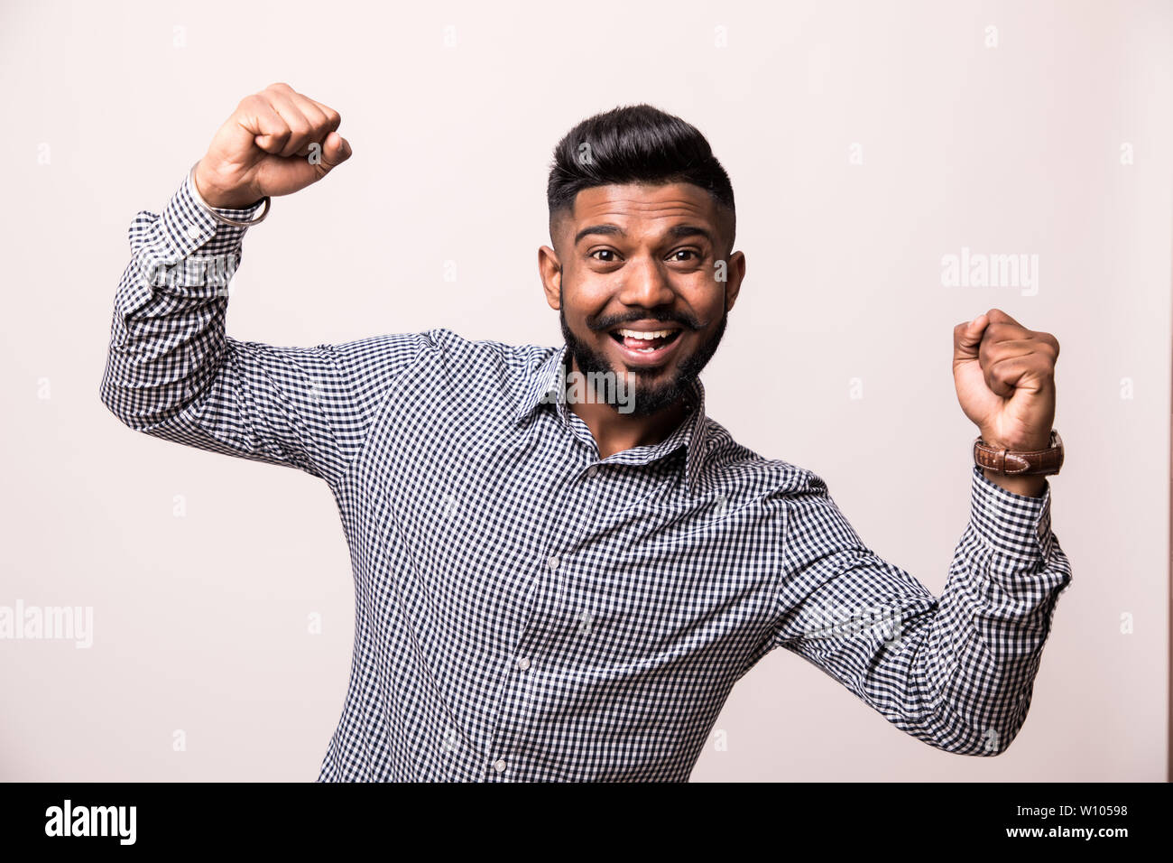 Happy young Indian man gesturing and smiling while standing against ...
