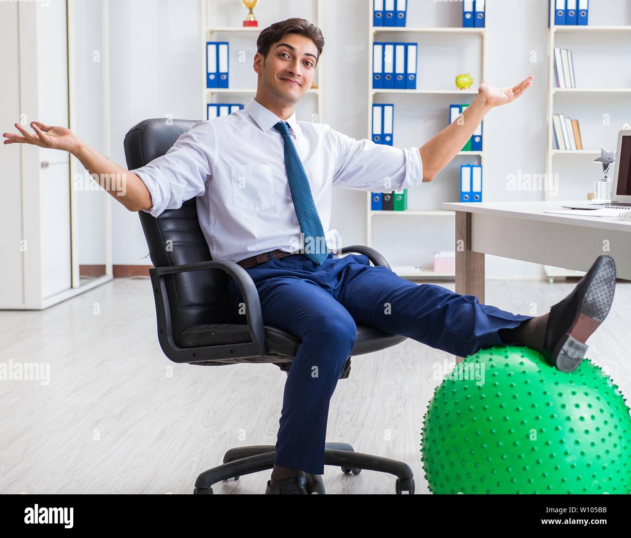 Young businessman doing sports stretching at workplace Stock Photo - Alamy