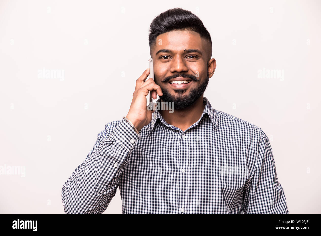 Young happy Indian man talking on mobile phone isolated against white ...