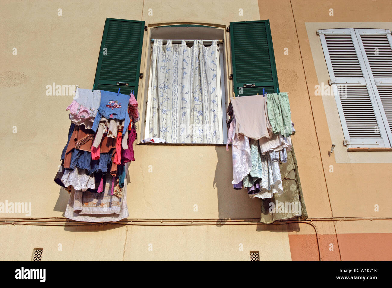 Laundry is hanging from shutters to dry from a window in Cannes, France ...